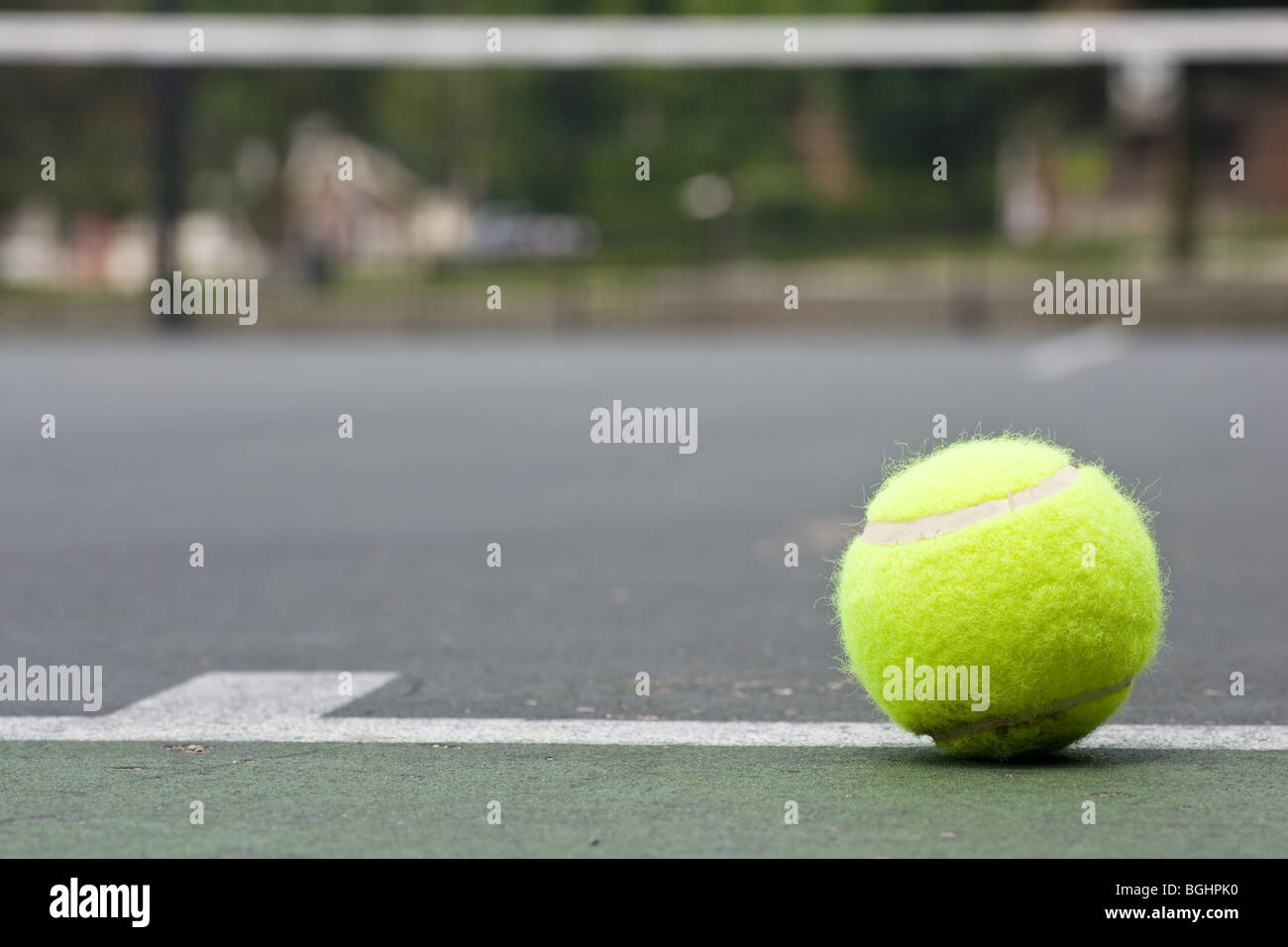 A closeup of a yellow tennis ball just outside of the base line on an ...