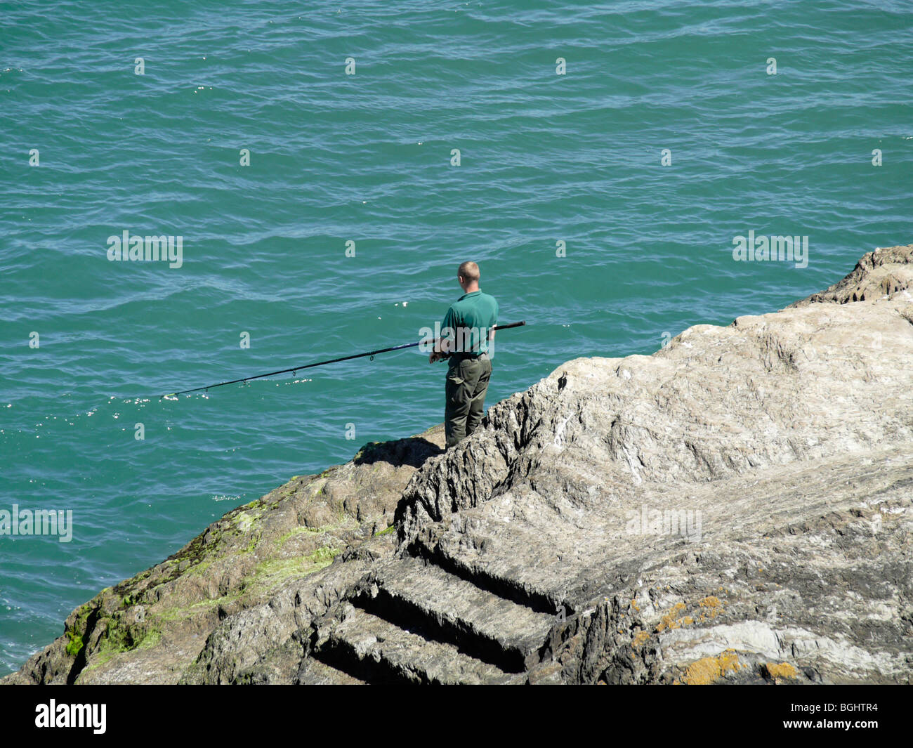 man fishing in the sea on a pier in the devon holiday town and resort ...