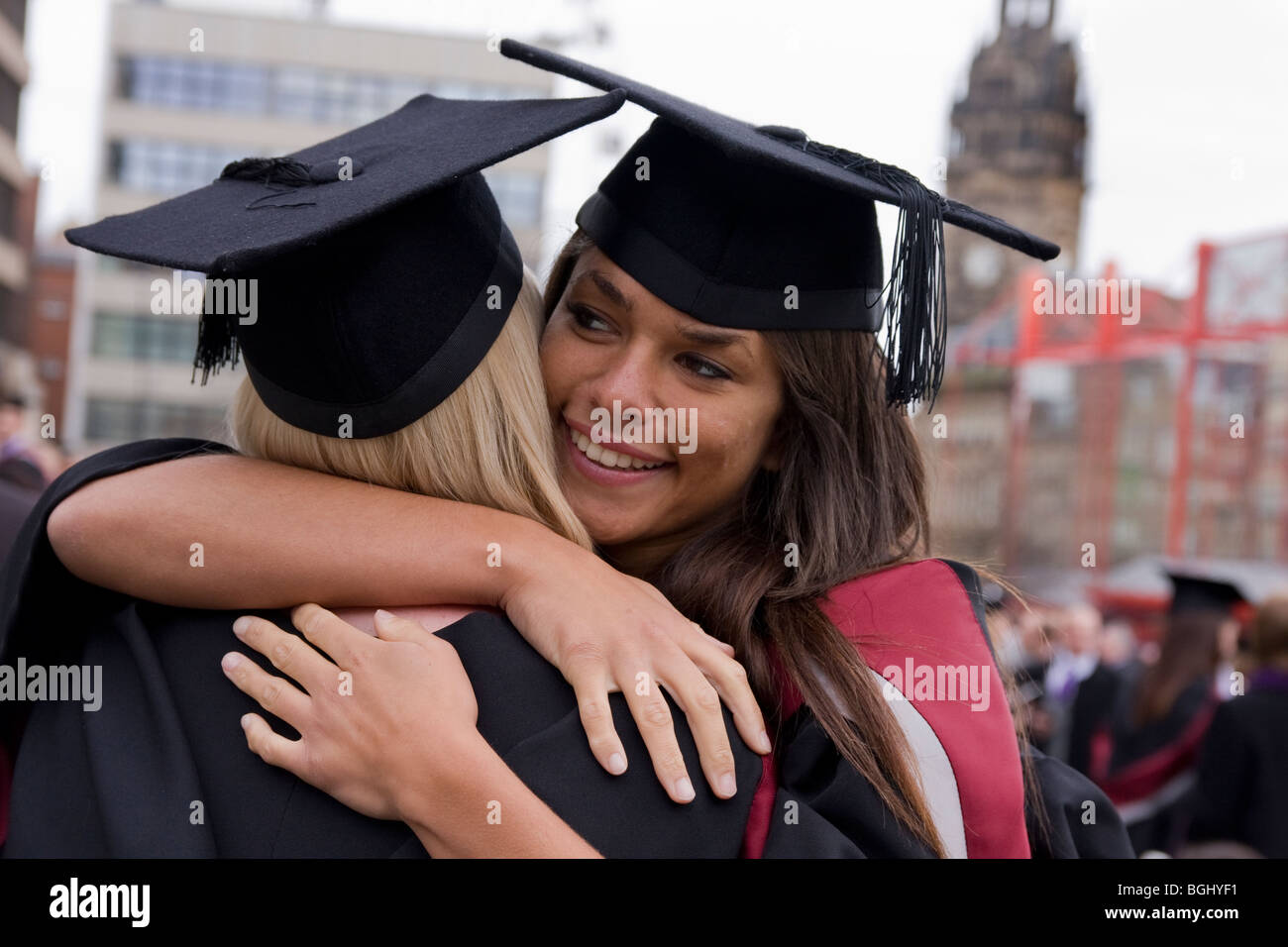 a young woman on graduation day hugging her fellow graduate Stock Photo ...