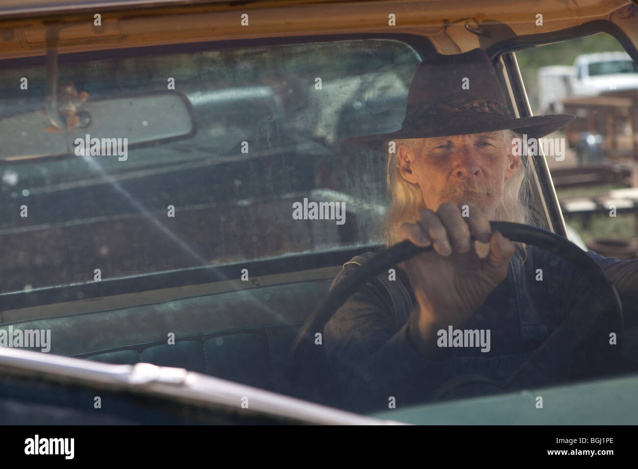An elderly man with a white beard driving a pickup truck and staring ...