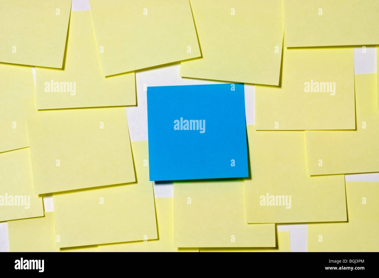 A blue note is the center of attention among yellow notes Stock Photo ...