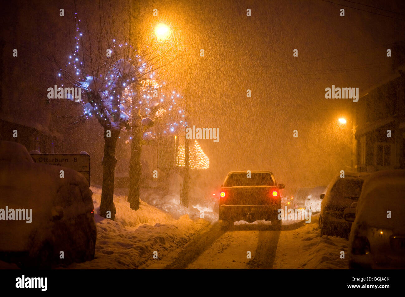 Car drives down a snow covered road at night. street lights and ...