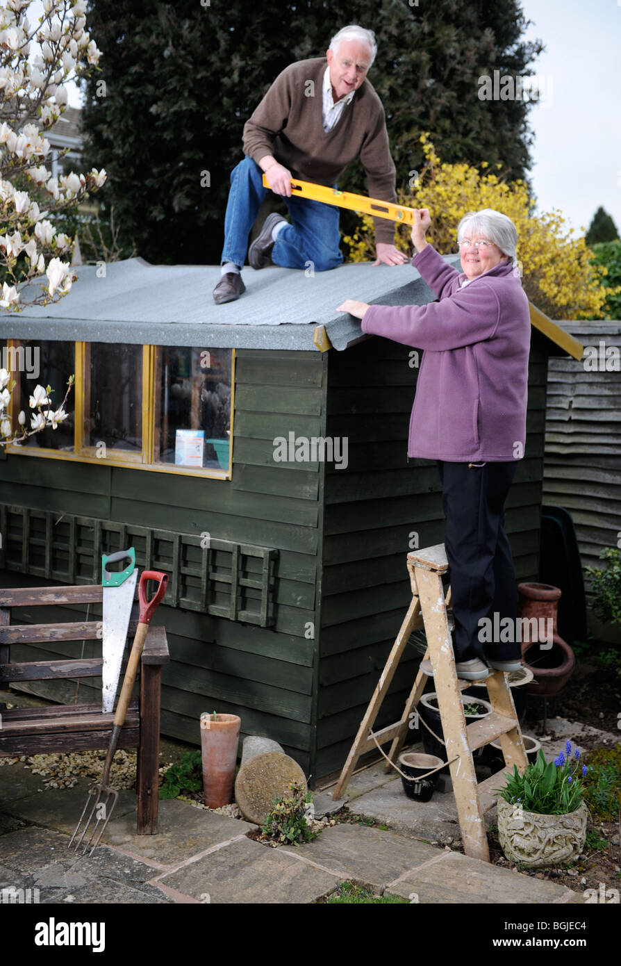 Two retired people re-felting a shed roof UK Stock Photo - Alamy