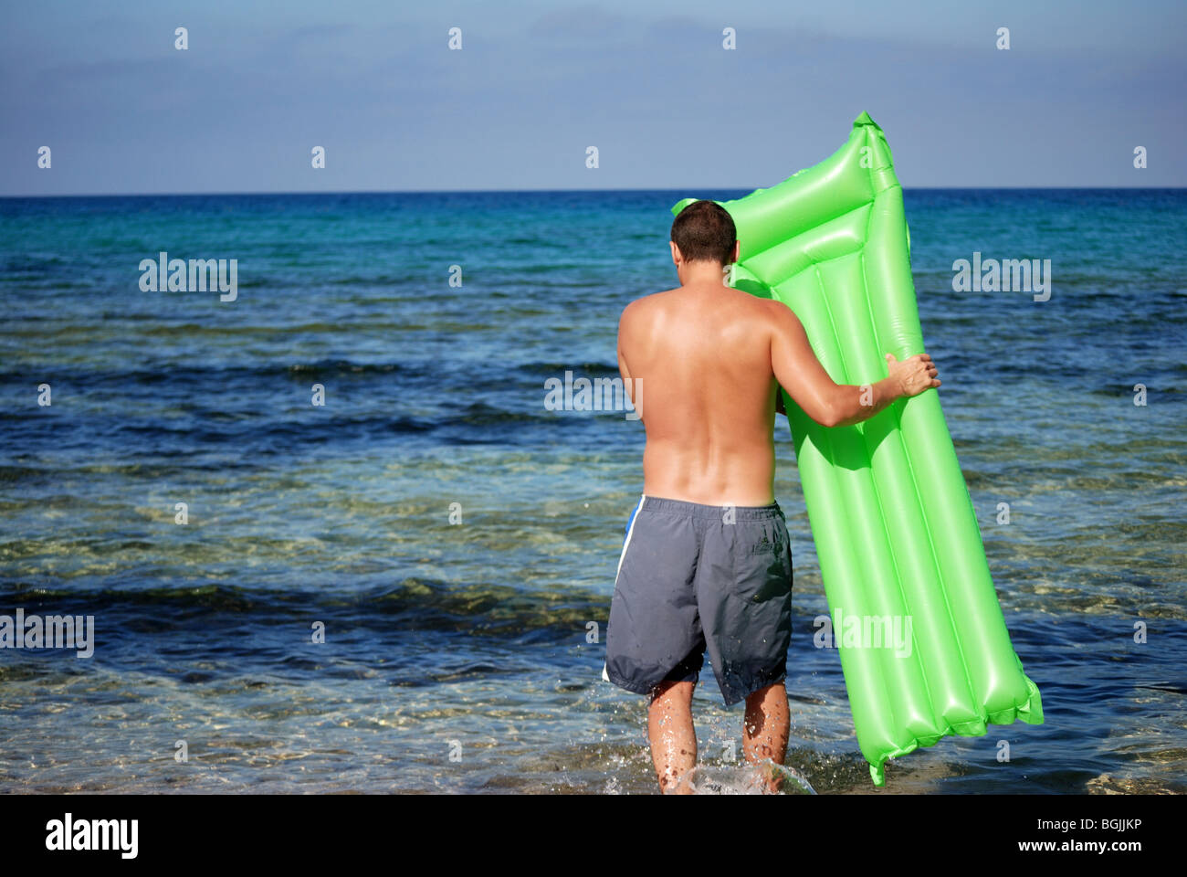 Man on beach with lilo Stock Photo - Alamy