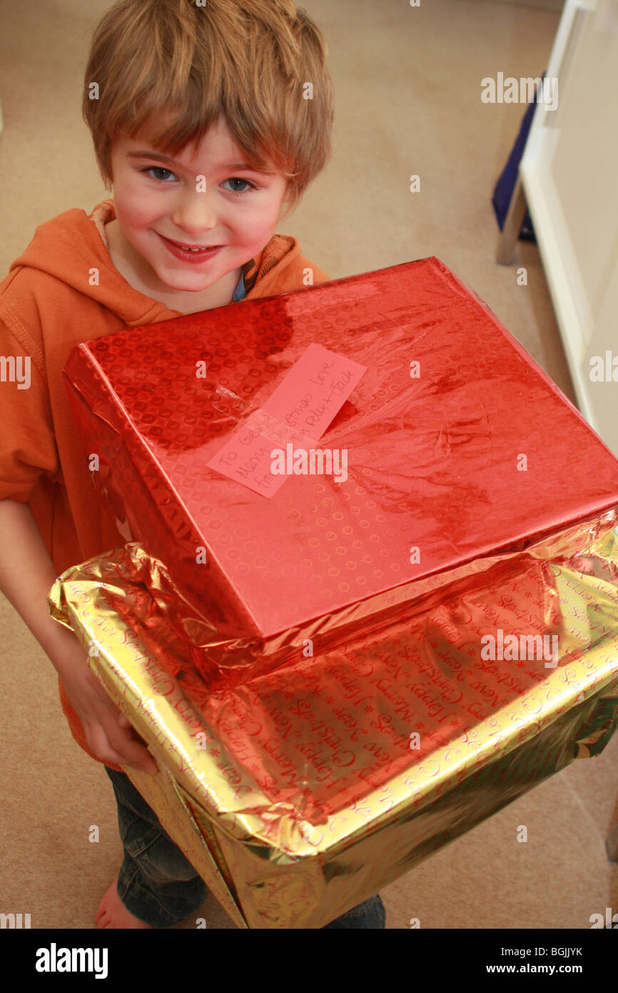A boy carrying a pile of Christmas presents Stock Photo - Alamy