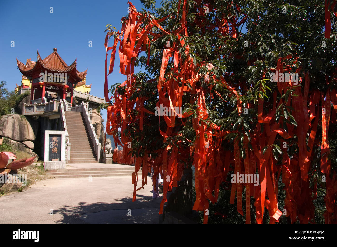 Red prayer ribbons in a tree near a Buddhist pavilion on Jiuhua Shan ...