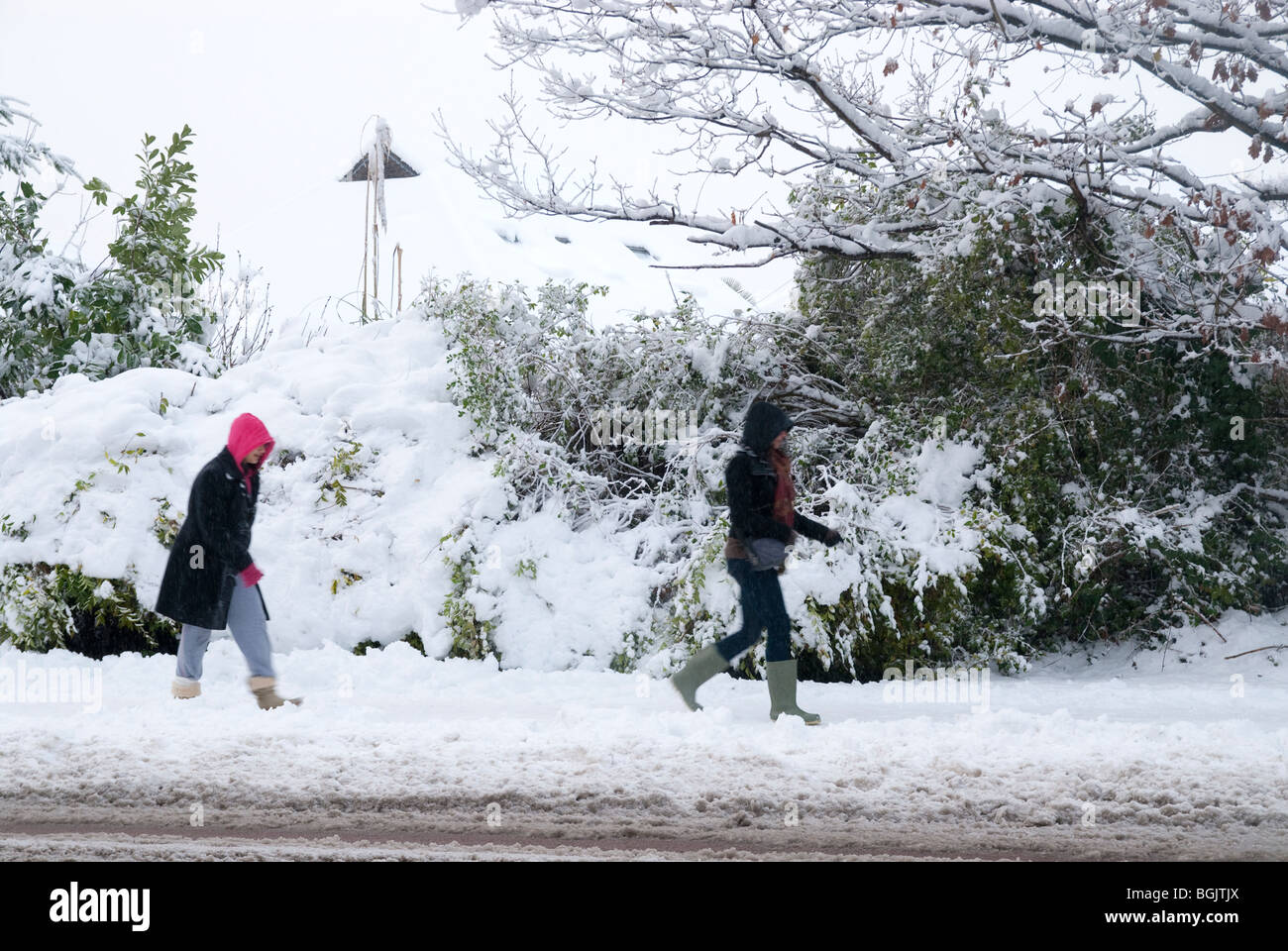 two people walking along urban snow covered path. Major snow fall A3 ...