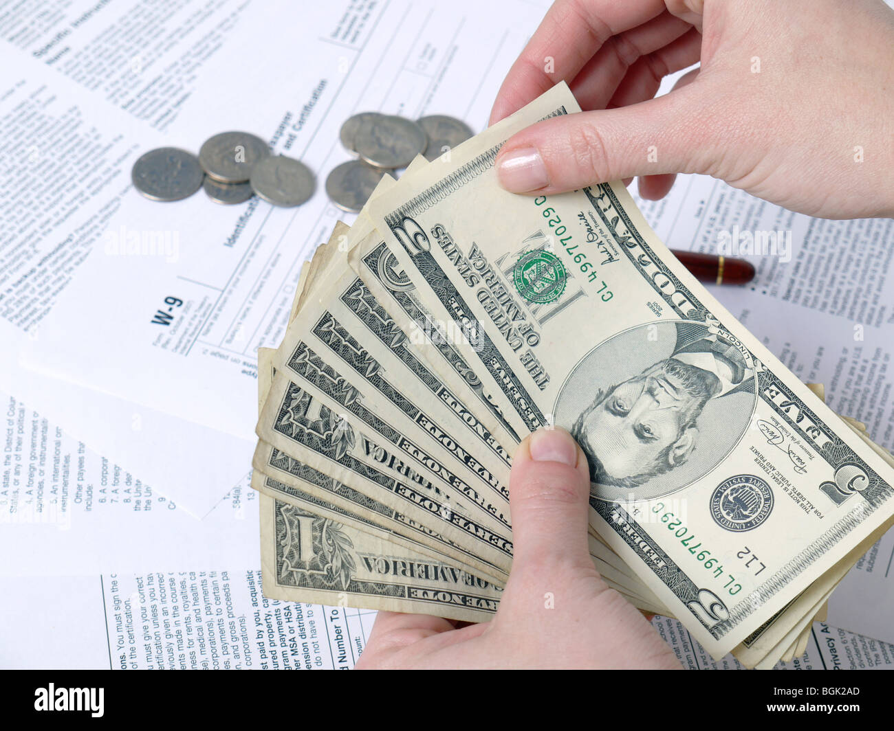 Closeup of female hands counting tax money over W-9 income tax forms ...