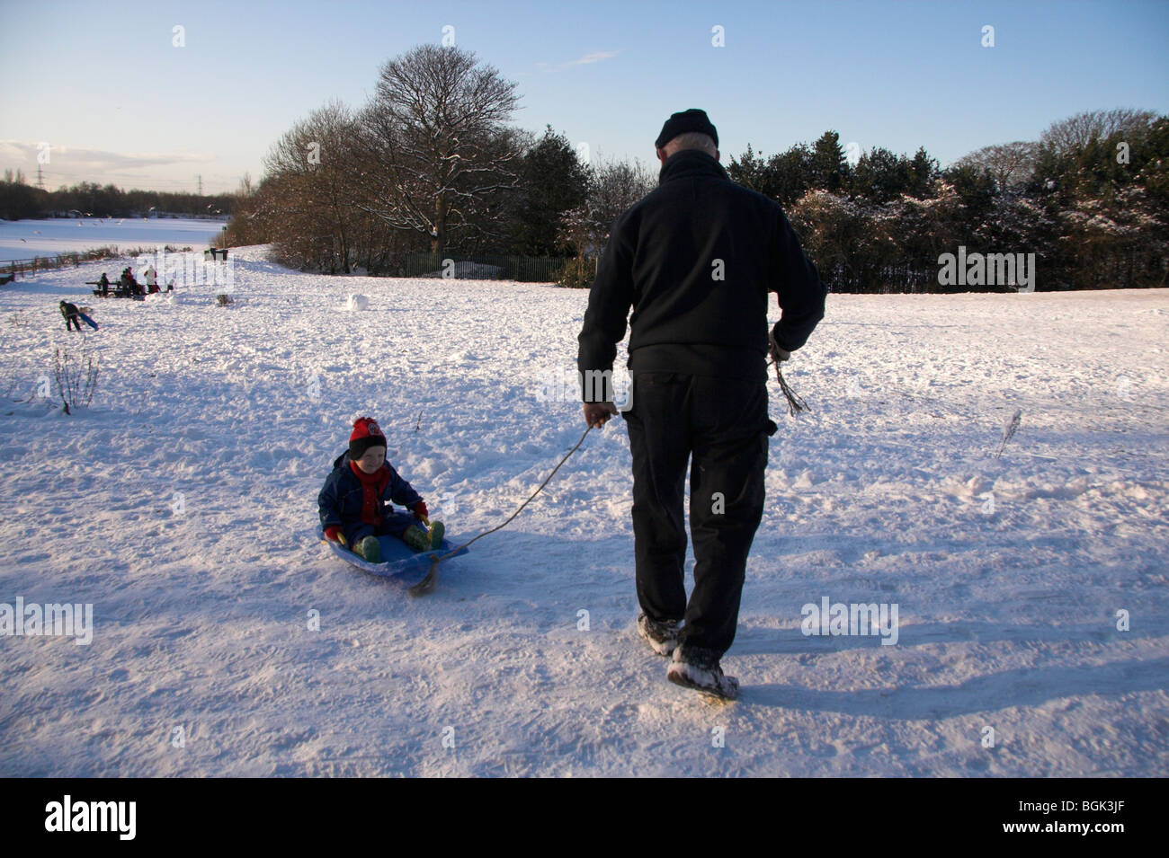 Man pulling a small child on a sledge, Chorlton Water Park, Manchester ...