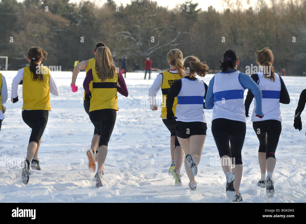 Teenage girls starting cross-country race in snow seen from behind ...