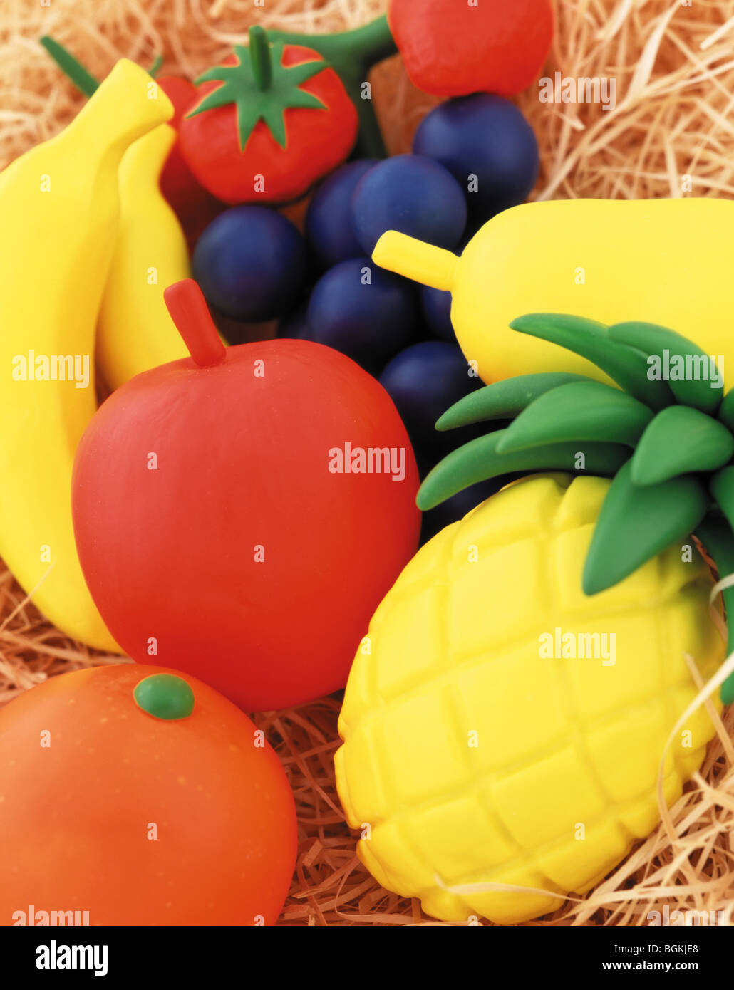Plasticine fruit on bed of hay Stock Photo - Alamy