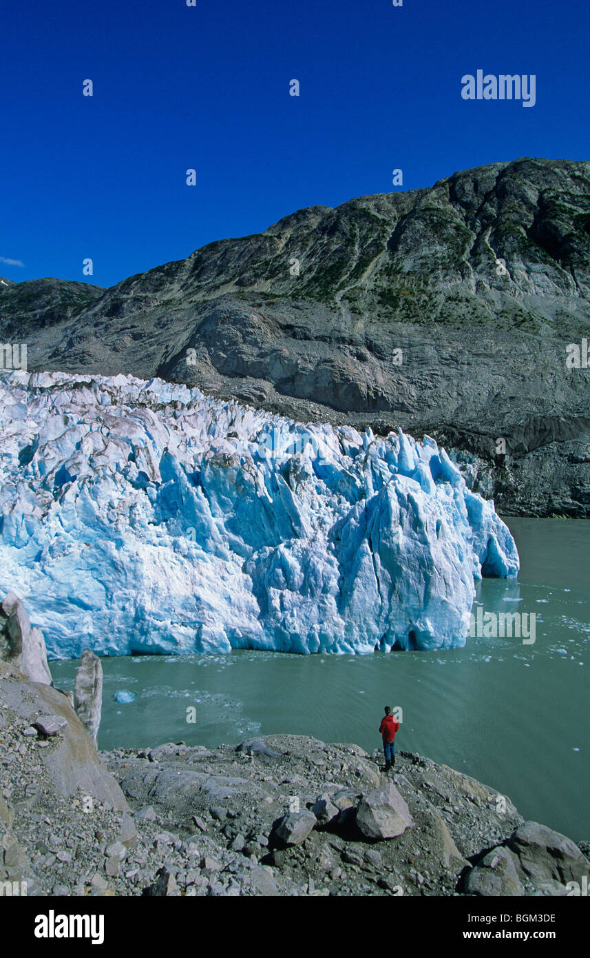 Hiker on cliffs above the face of McBride Glacier in Muir Inlet ...