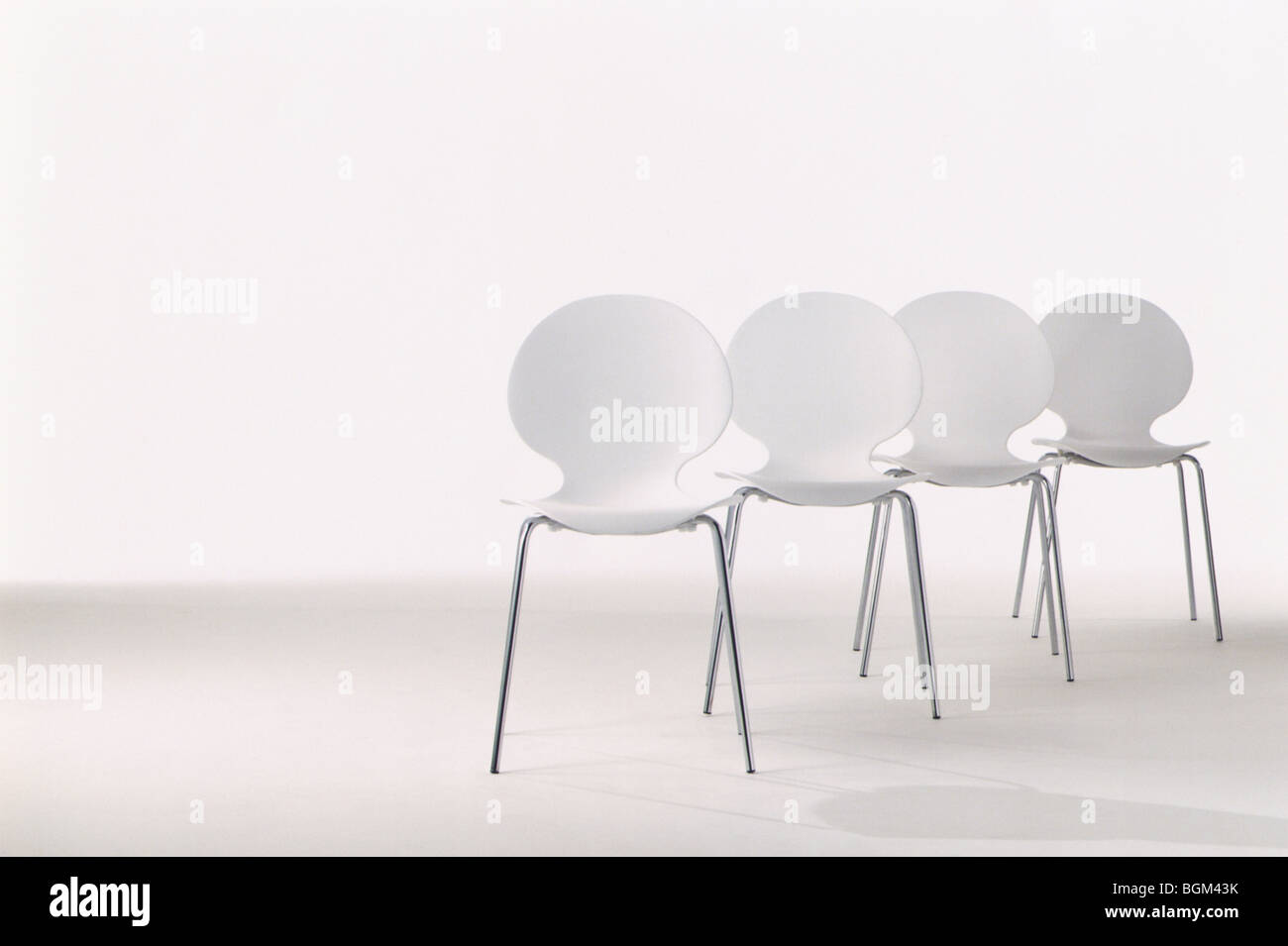 Four white chairs in a row Stock Photo - Alamy