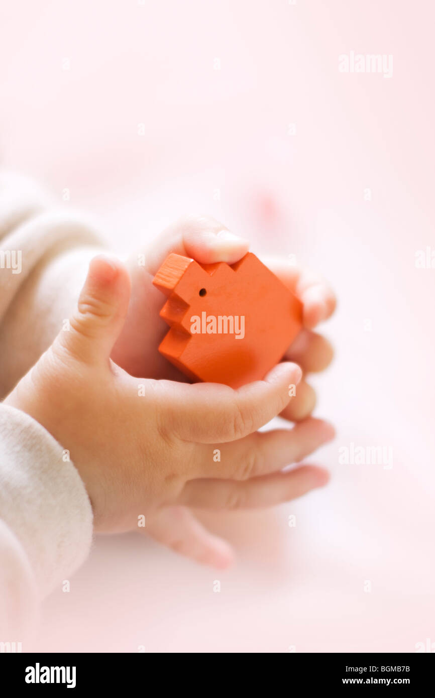 Baby holding orange toy block Stock Photo - Alamy