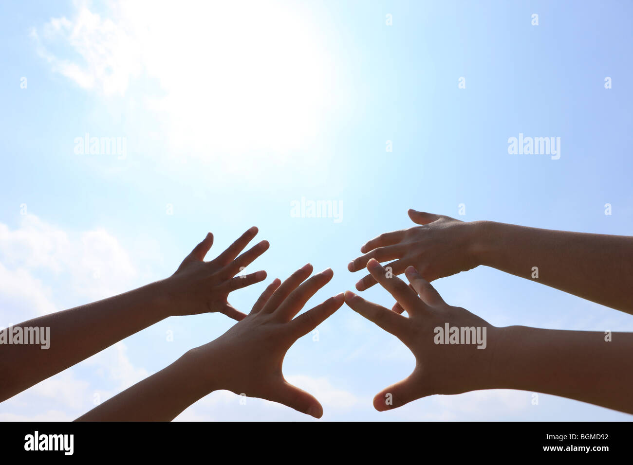 Four children's hands reaching towards sky Stock Photo - Alamy