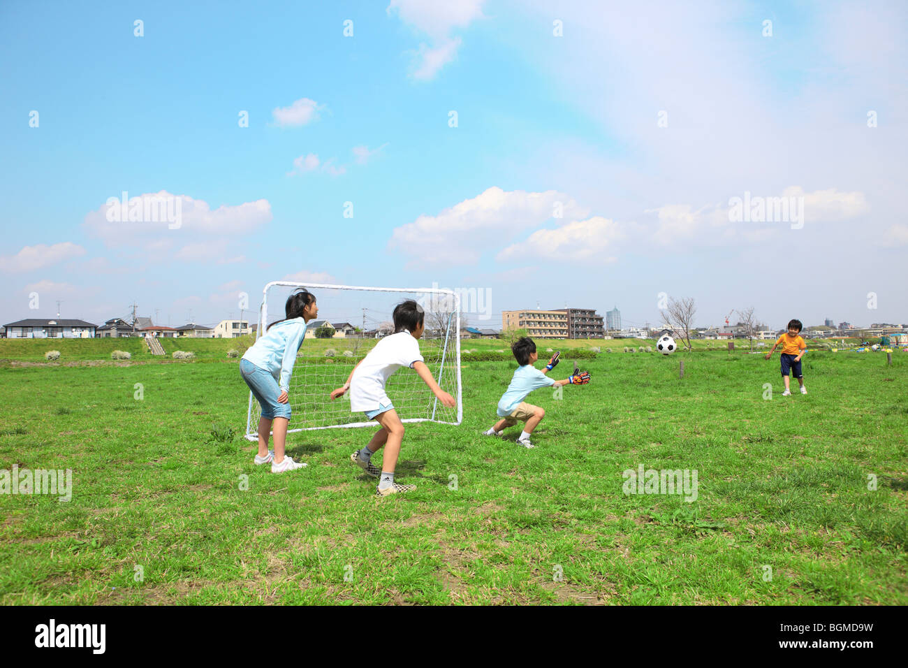 Four children playing soccer near goal posts. Futako-tamagawa, Setagaya ...