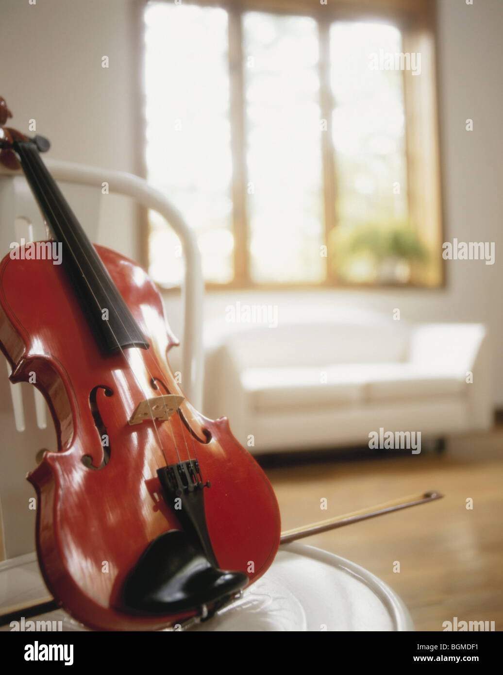 Violin on chair in bright living room Stock Photo - Alamy