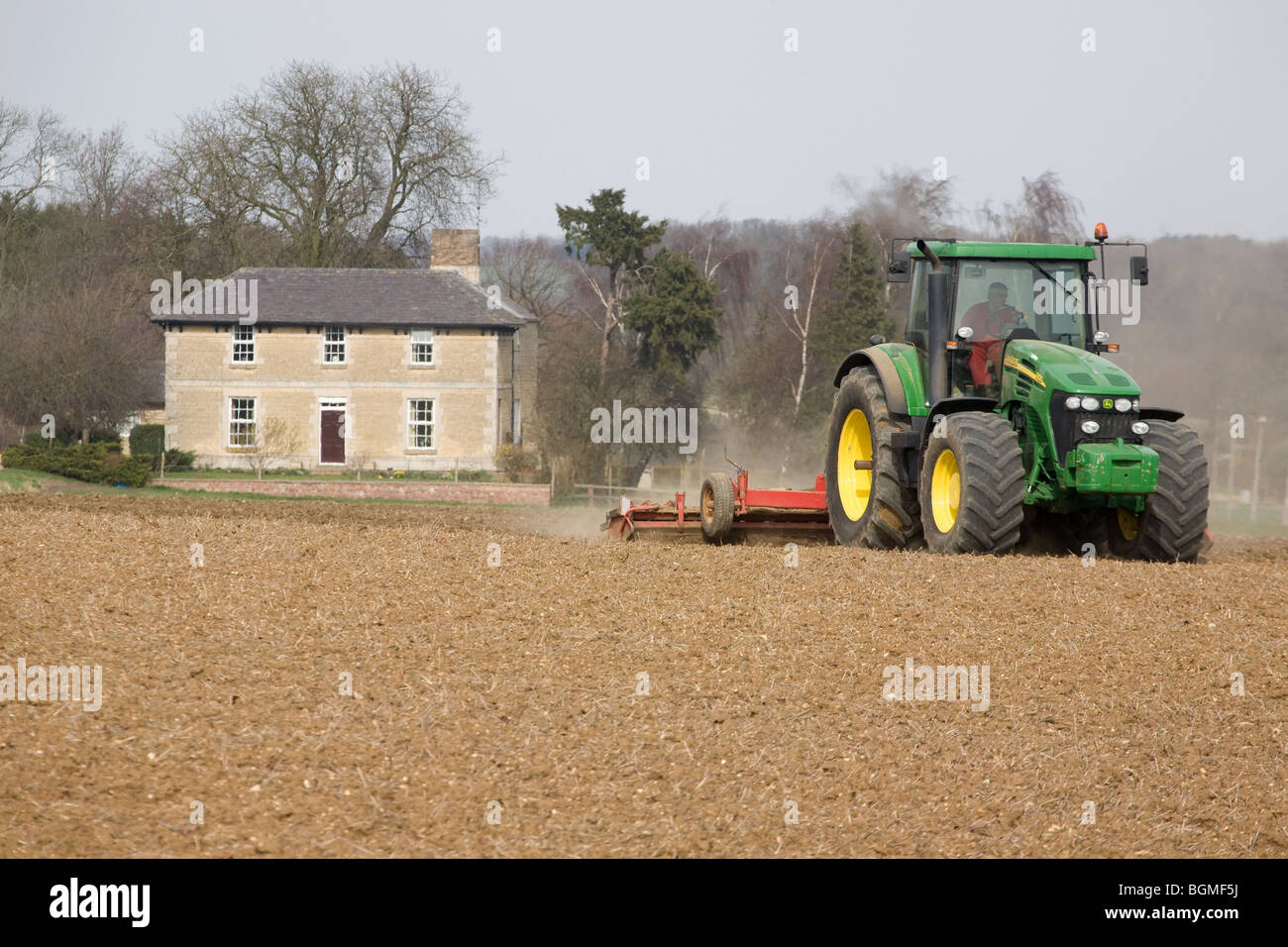 Tractor working on land in front off a farmhouse Stock Photo - Alamy