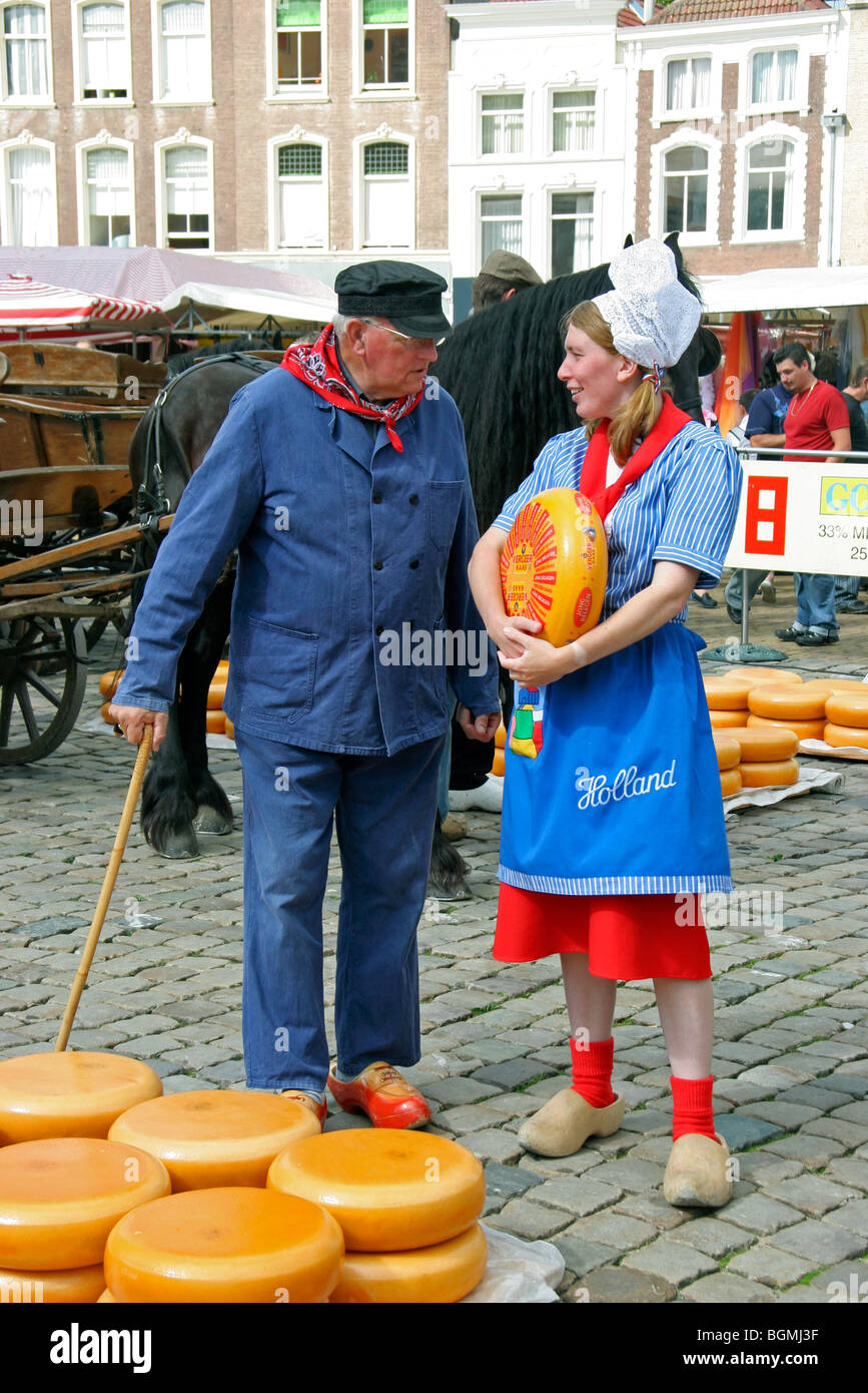 Farmer and girl in traditional dress on wooden clogs carrying wheel at ...