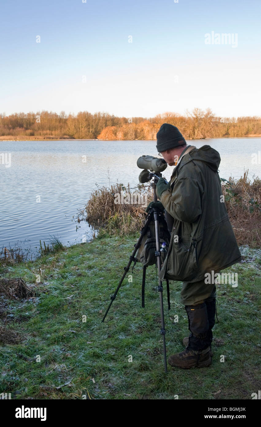 A birdwatcher looking through his telescope at Spade Oak lake Bourne ...