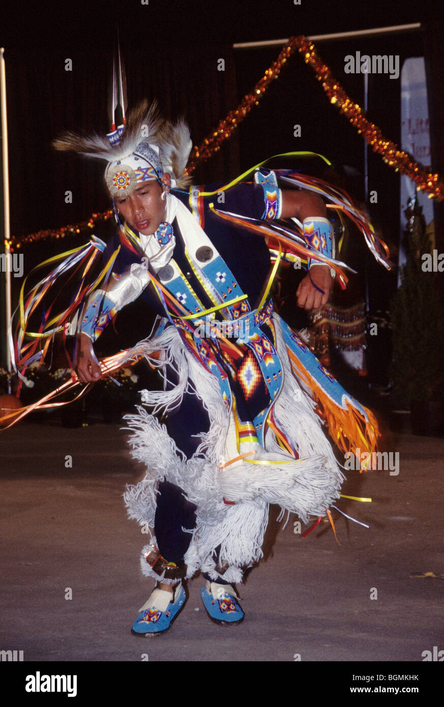 Young man dressed in pow wow regalia demonstrates a grass dance during ...