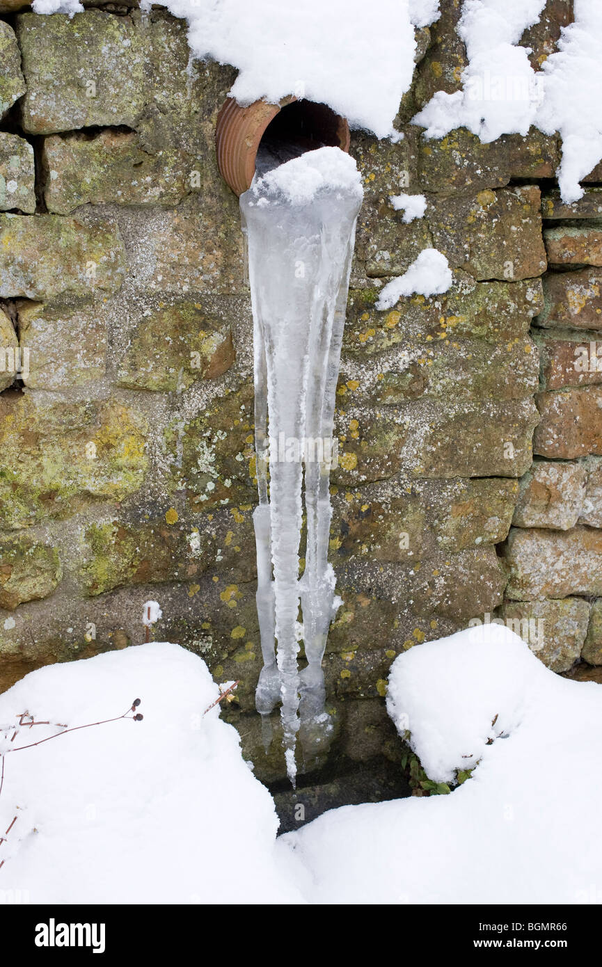 A snow covered frozen overflow pipe/ drainpipe in a snowbound village ...