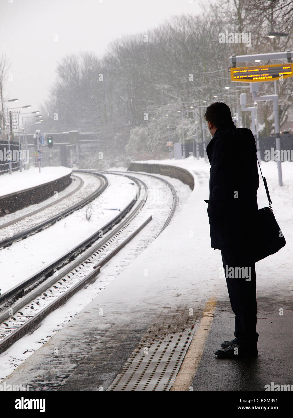 Commuter waiting for a train delayed by snow at a suburban railway ...