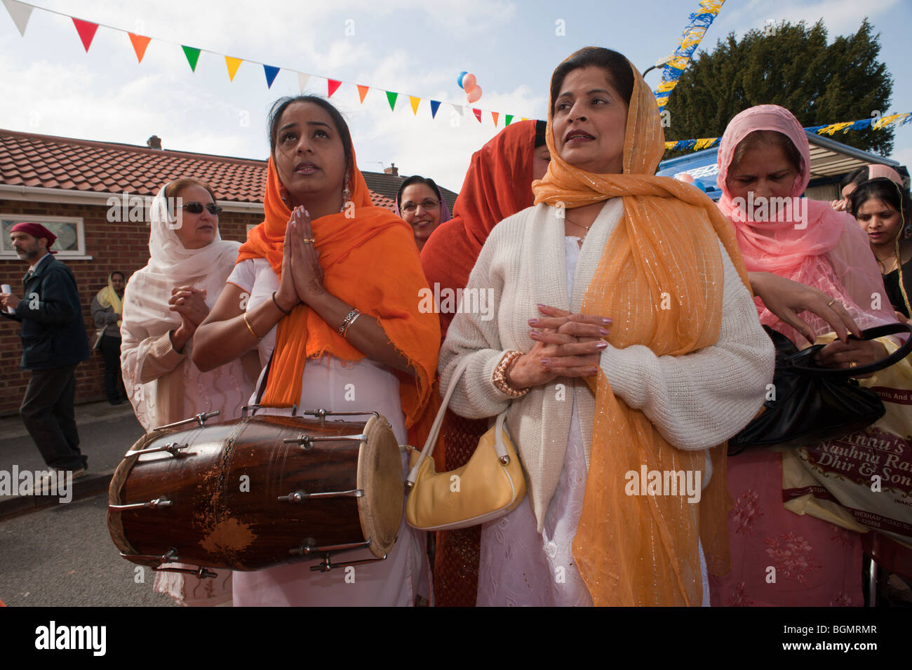 Women, one with drum, wait in prayer for the start of the Vaisakhi ...