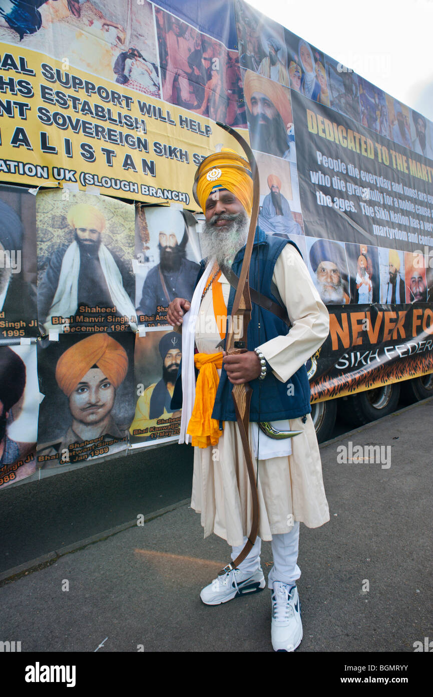A Sikh man in warrior dress with bow poses in front of a float ...