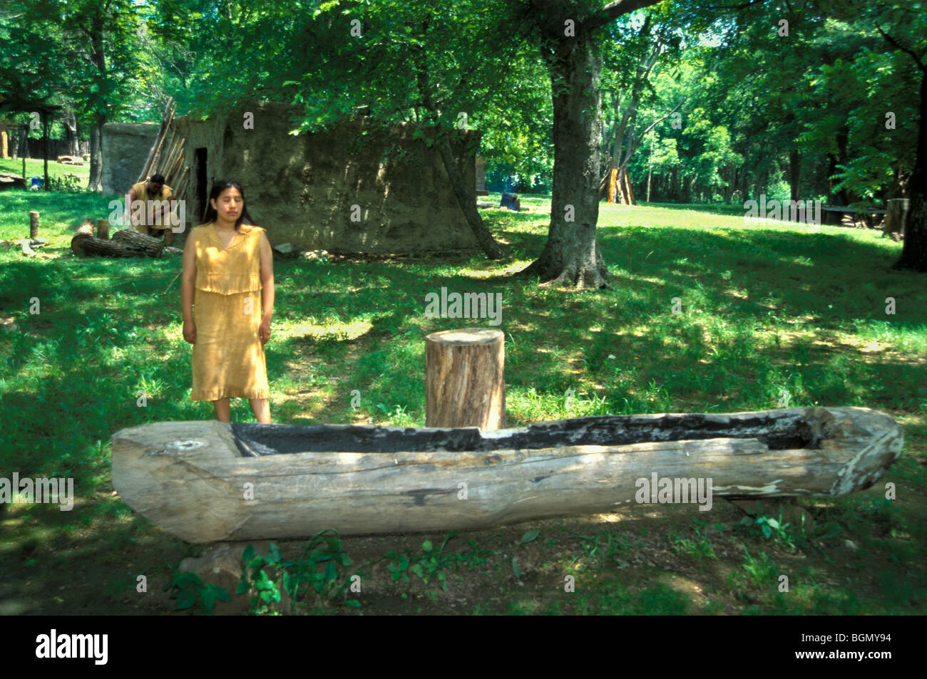 Traditional Cherokee village with woman in buckskin dress standing next ...