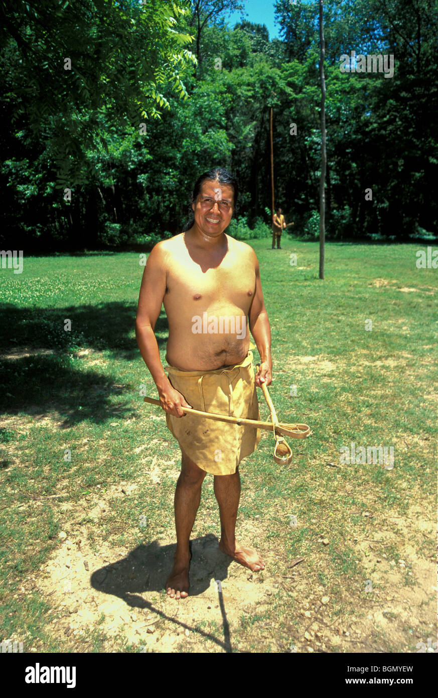Cherokee man dressed in traditional deerhide clothing holds a pair of ...