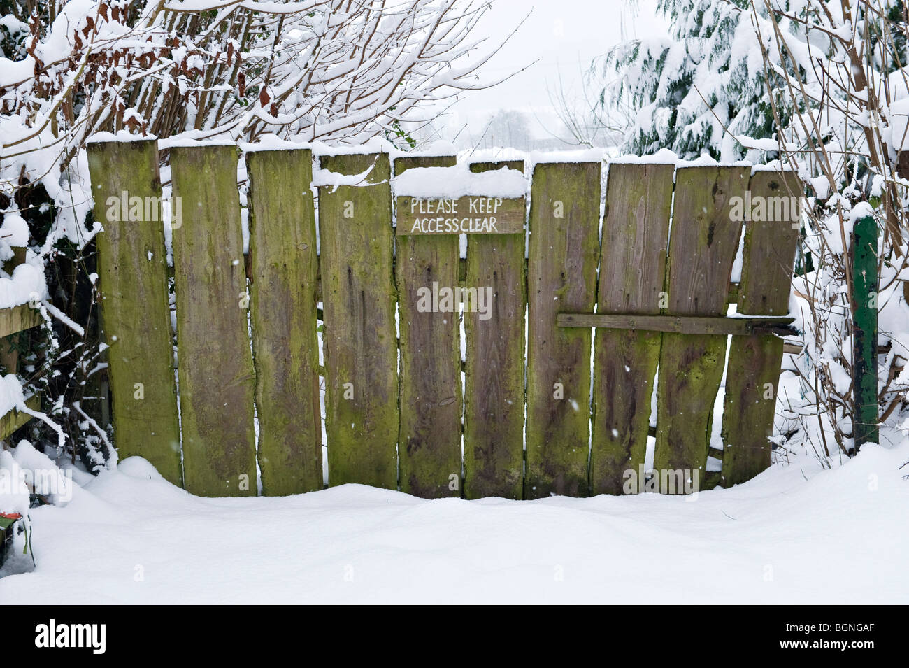 A gate blocked by heavy snow in winter, with sign reading 'Please Keep ...