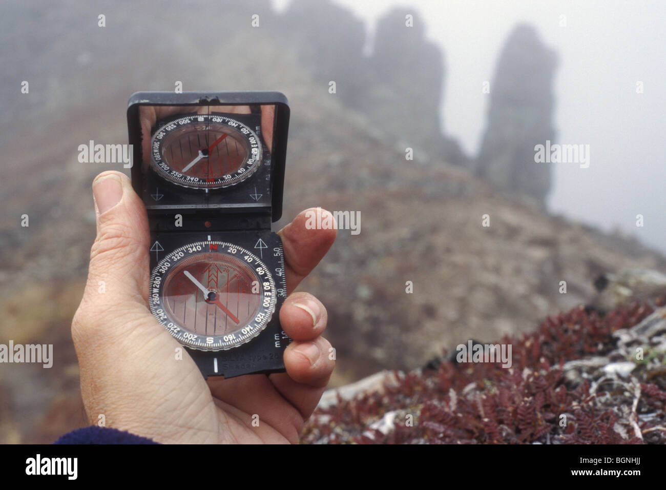 Hiker reads compass for orientation in the fog in the mountains Stock ...