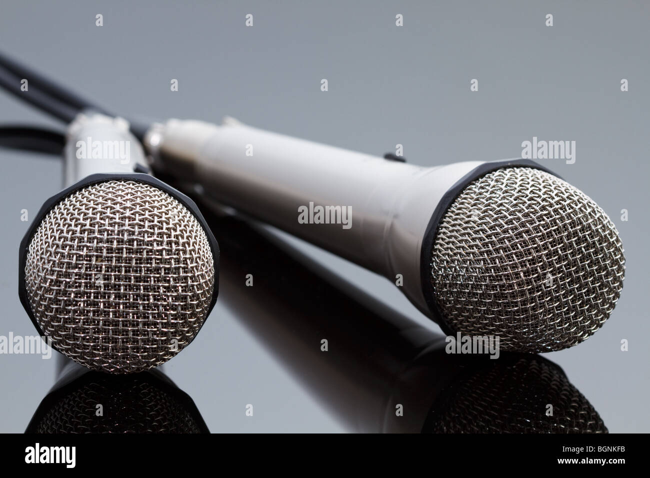 Two microphones on reflecting black background Stock Photo - Alamy
