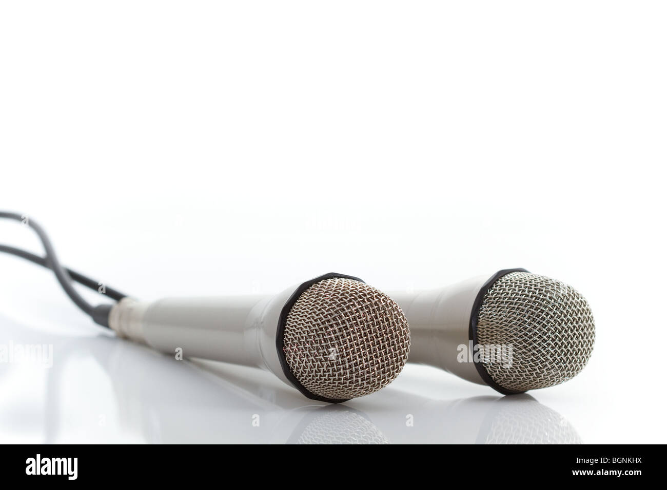 Two microphones on reflecting white background Stock Photo - Alamy