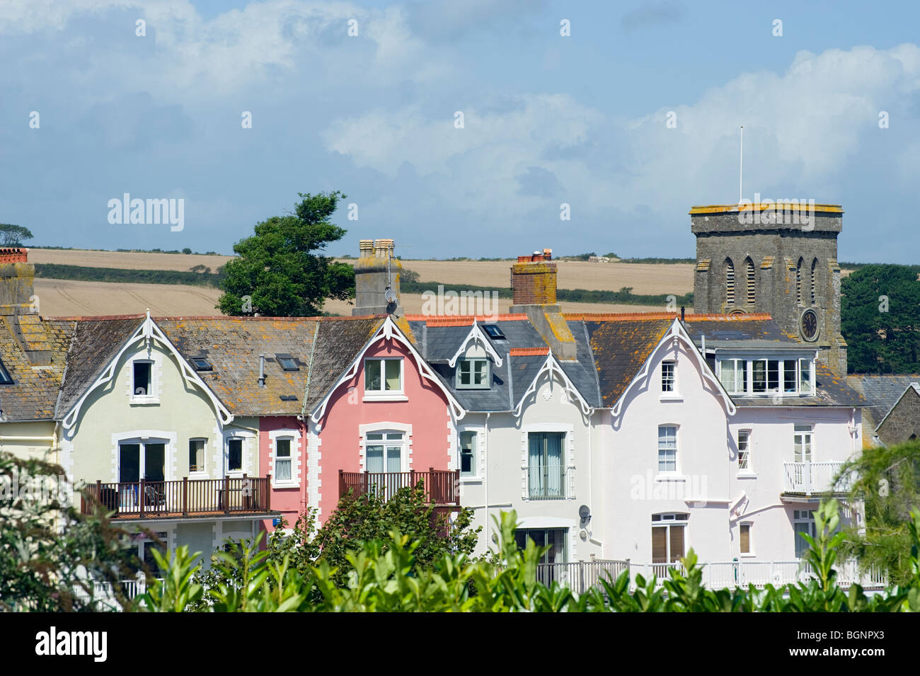 A view of a colourful housing terrace in Salcombe with a church and ...