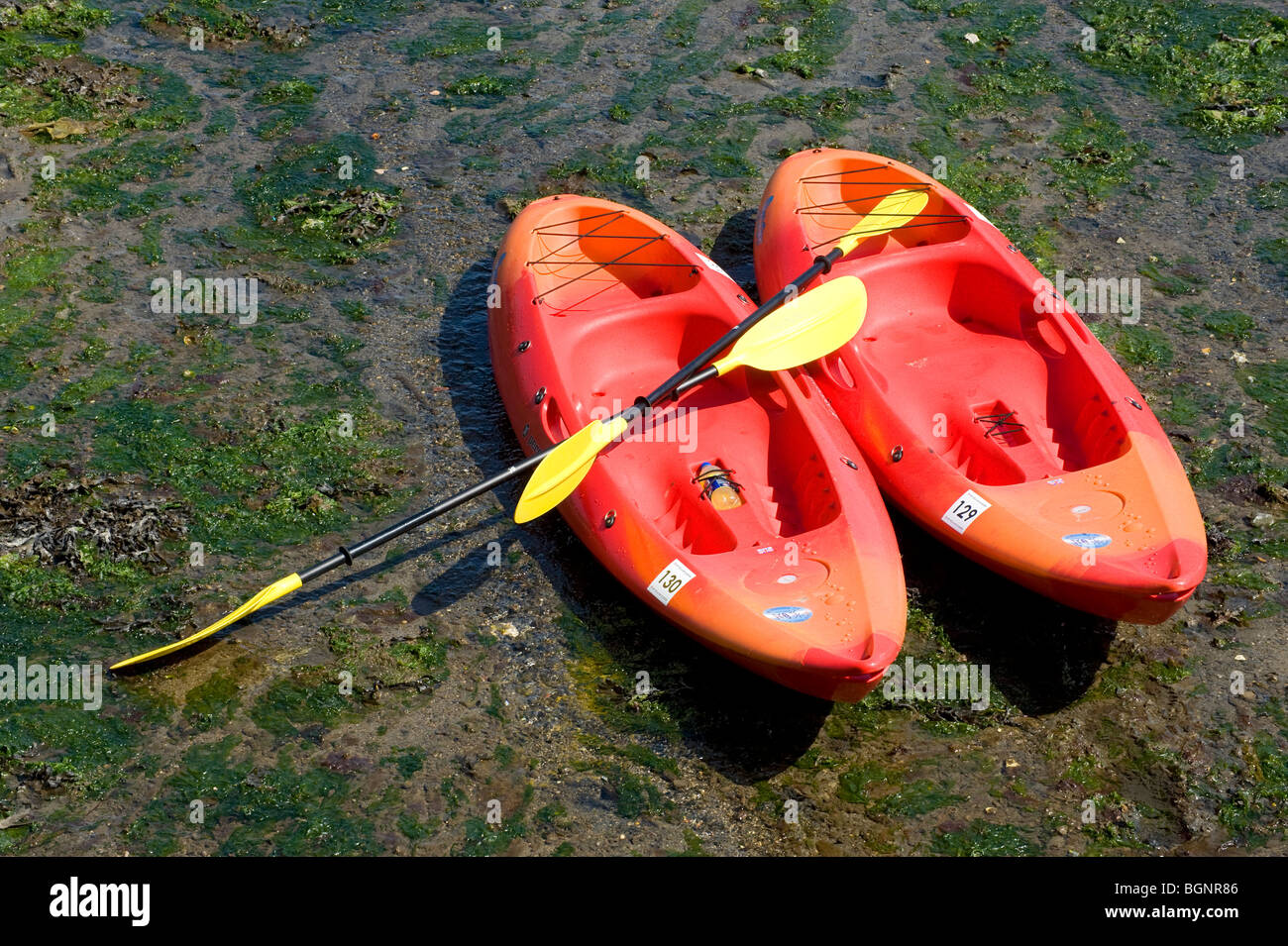 A pair of orange and red kayaks on the beach at Salcombe, Devon,England ...