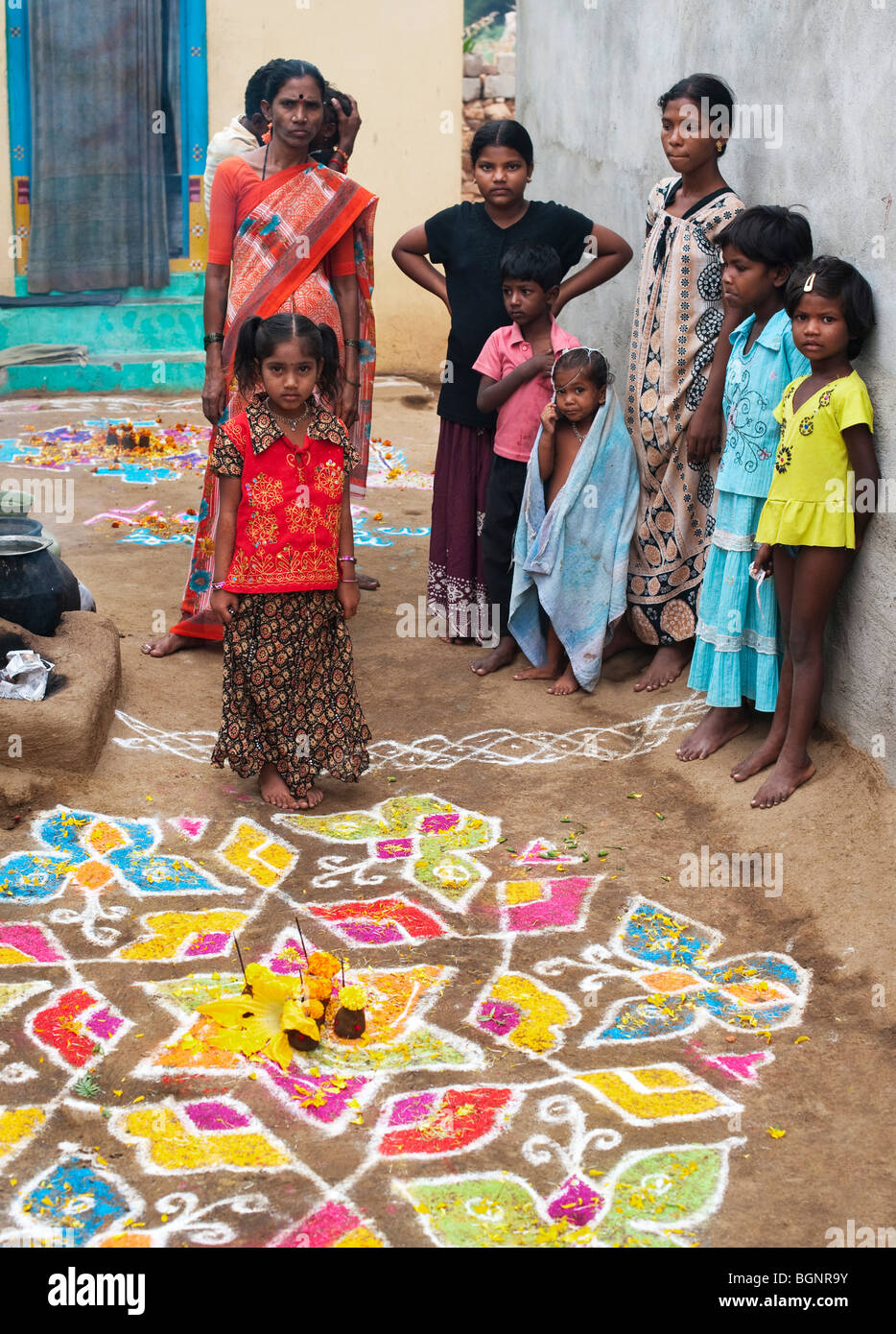Indian family outside their home in front of a rangoli design in the ...
