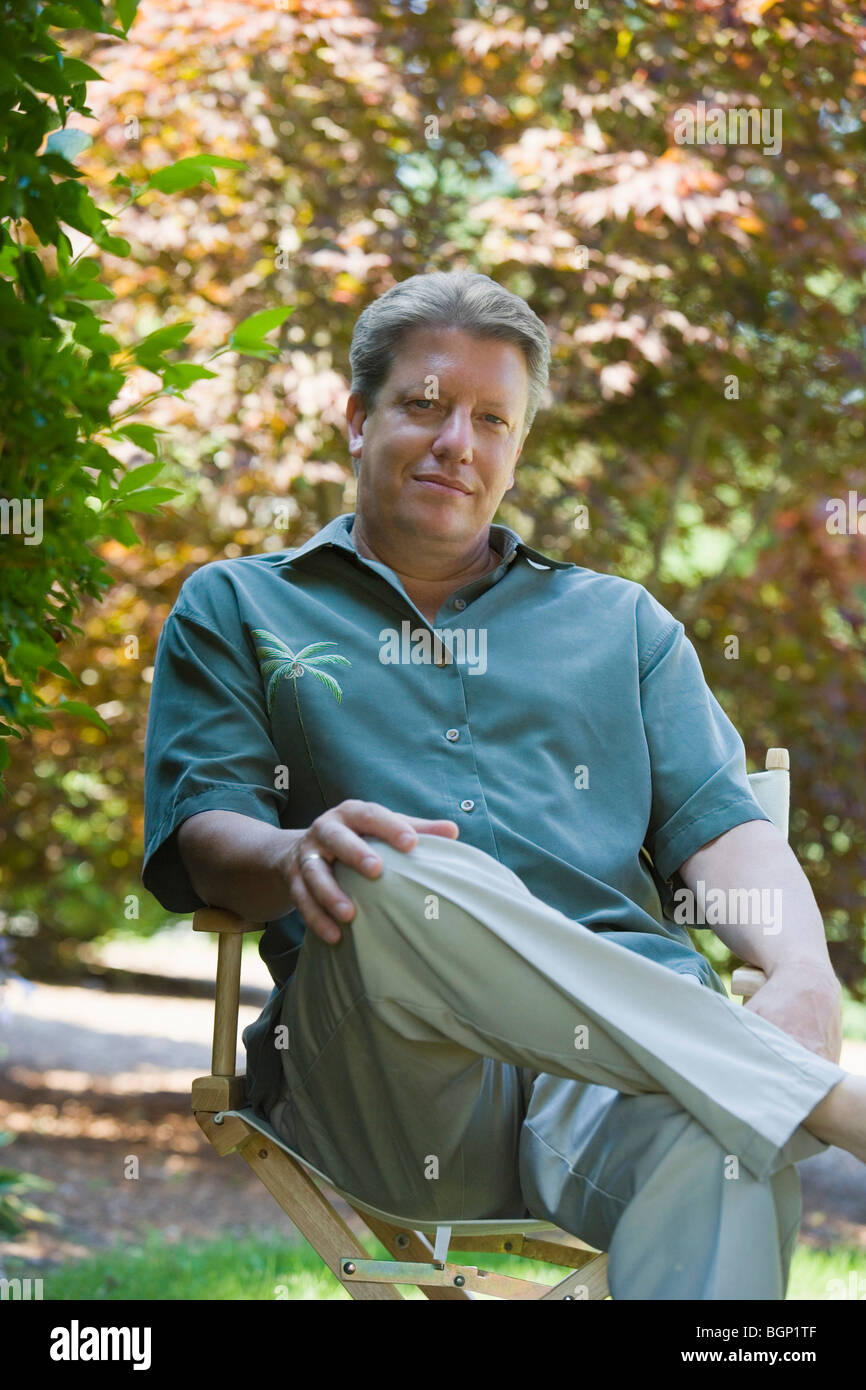 Portrait of a mature man sitting on a chair and smirking Stock Photo ...