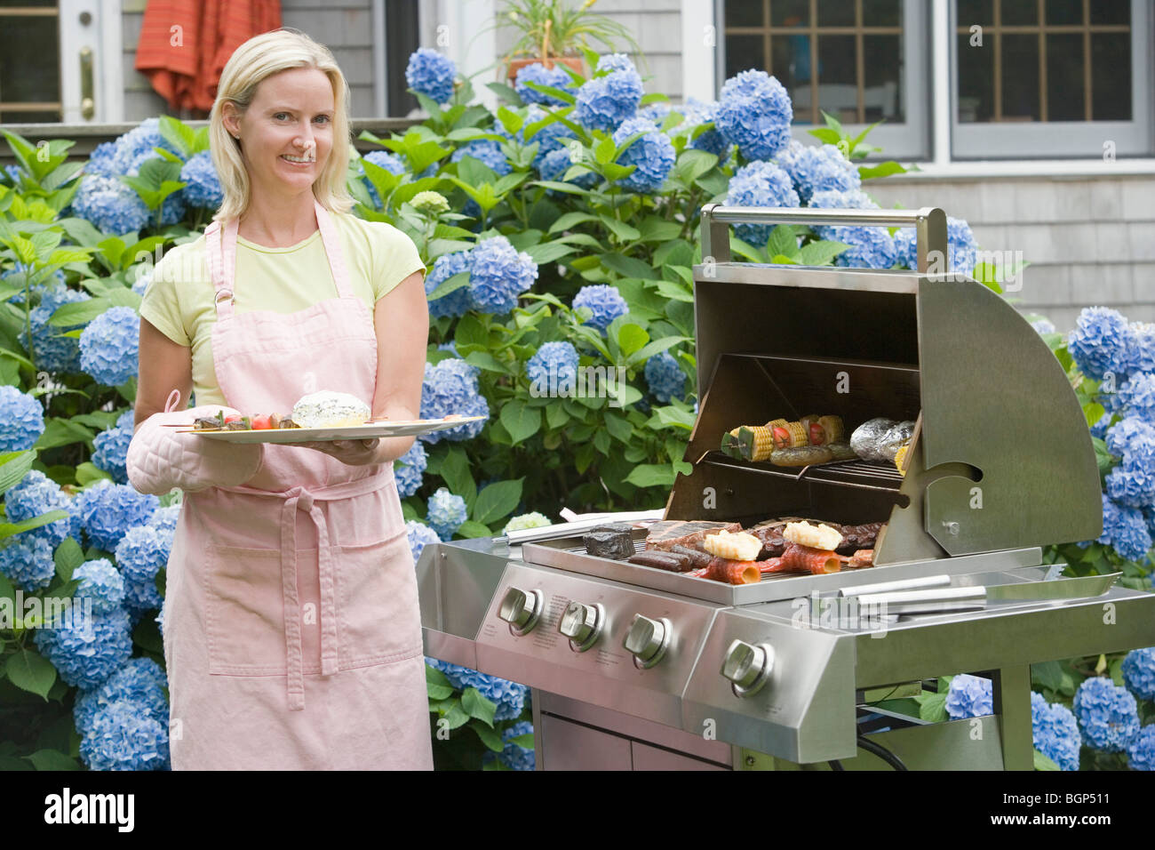 Portrait of a mid adult woman barbecuing in a lawn Stock Photo - Alamy