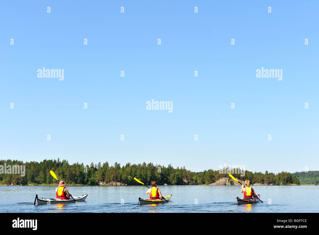 Three persons paddling kayaks in a lake, Sweden Stock Photo - Alamy