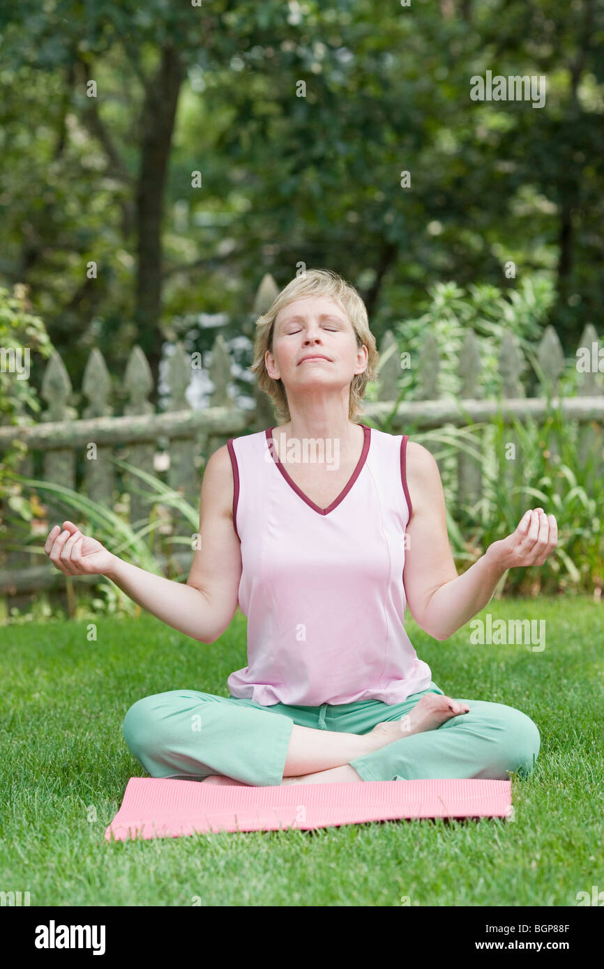 Mature woman doing yoga in a lawn Stock Photo - Alamy