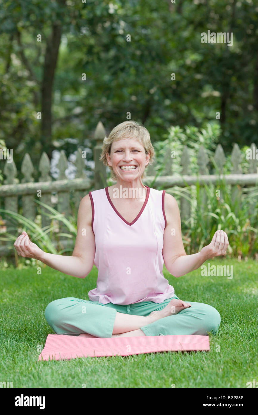 Portrait of a mature woman doing yoga in a lawn and smiling Stock Photo ...