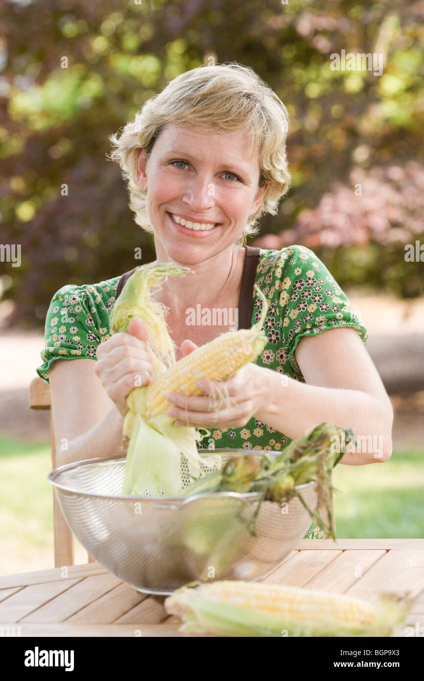 Portrait of a mature woman peeling a corn and smiling Stock Photo - Alamy