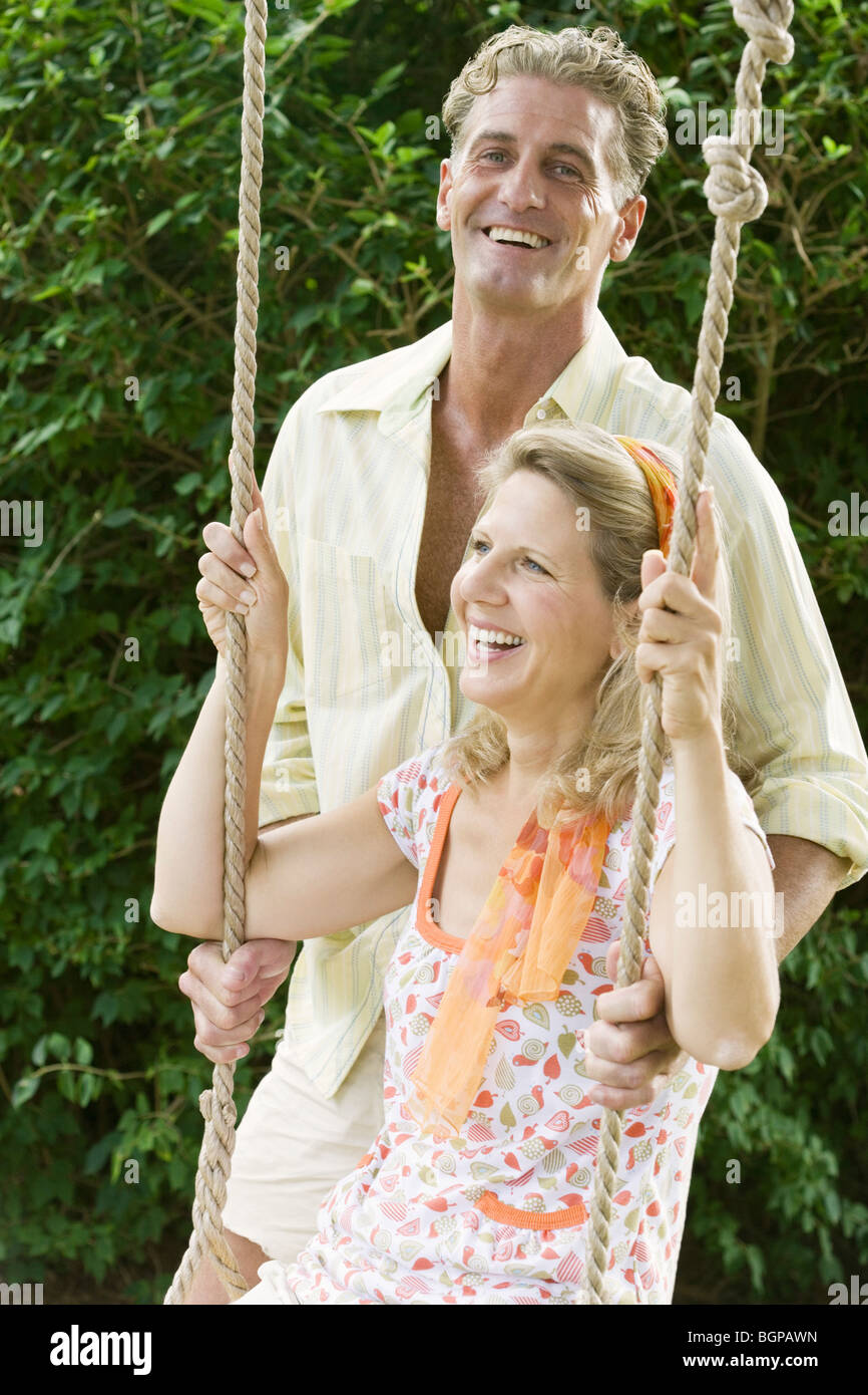 Mature man pushing a mature woman on a rope swing Stock Photo - Alamy