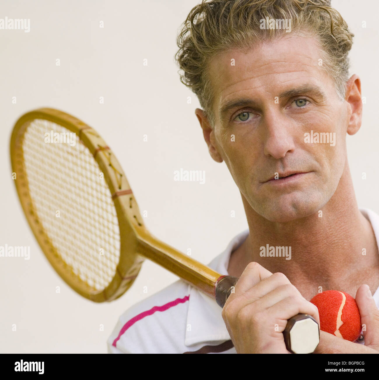 Portrait of a mature man holding a tennis racket and a tennis ball ...