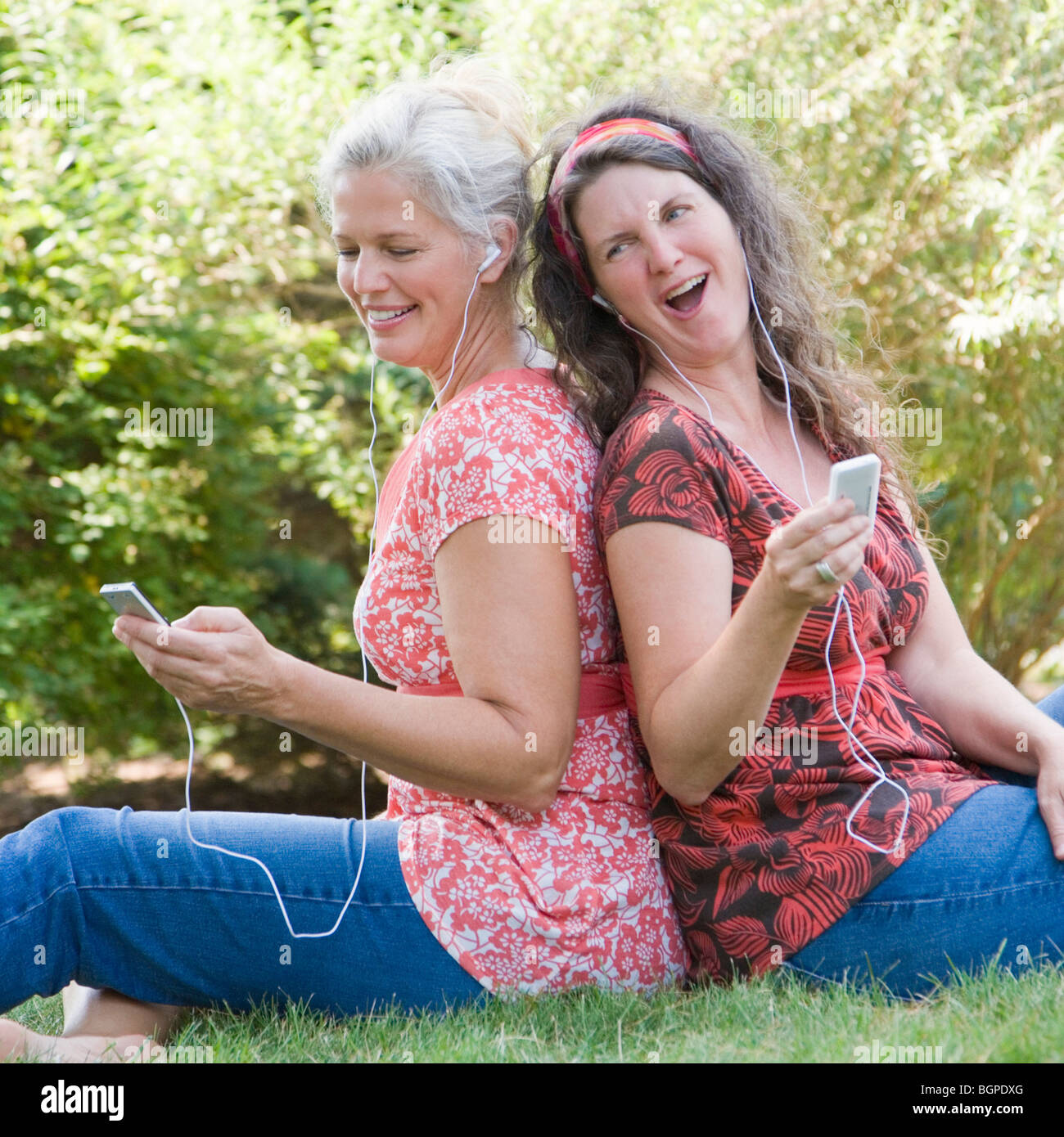 Side Profile Of Two Mature Women Sitting Back To Back In A Park And
