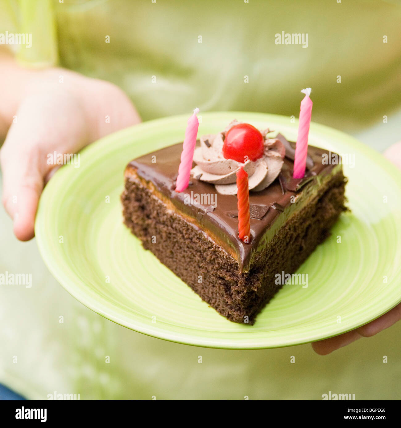 Mid section view of a woman holding a plate of birthday cake slice ...