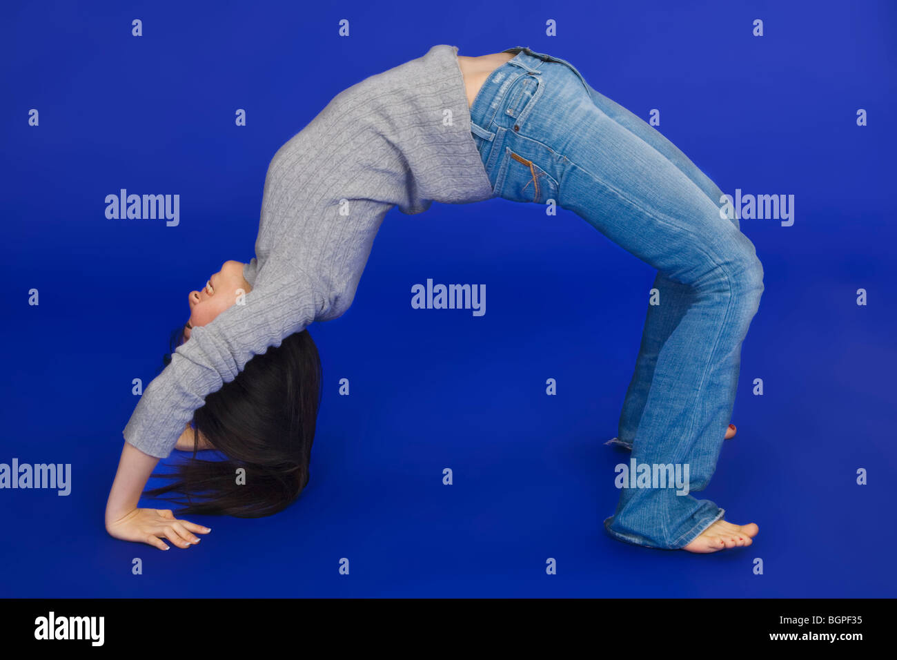 Female Asian teen doing a back bend on a blue background Stock Photo ...