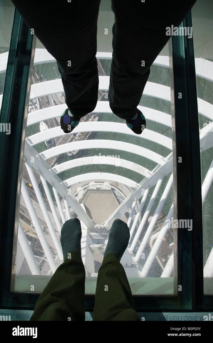 Visitors stand on the glass observation floor of the Spinnaker Tower ...